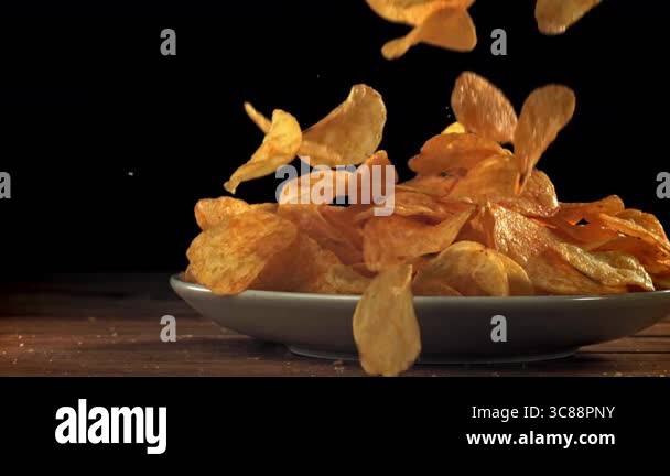 Potato chips fall on a wooden table. Filmed on a high-speed camera at ...