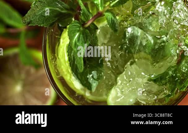 Ice falls into a mojito cocktail. Filmed on a high-speed camera at 1000 ...