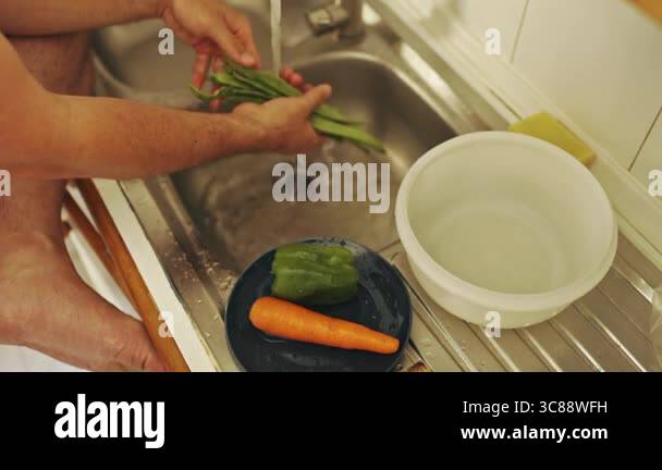Chef washing fresh green beans under running water in kitchen sink ...