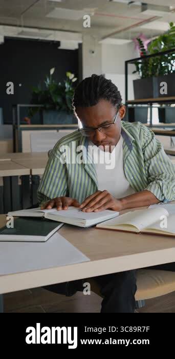 Focused African American student writing notes in a modern shared ...