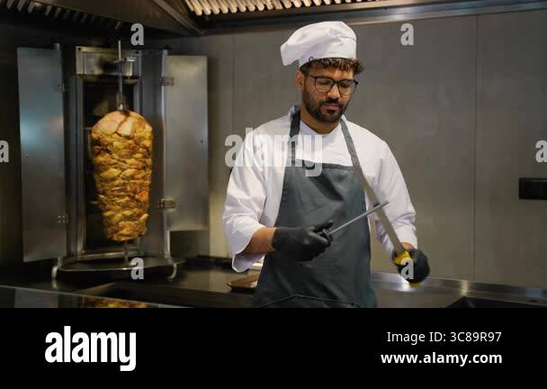 Professional chef in white uniform and gloves sharpening a carving ...