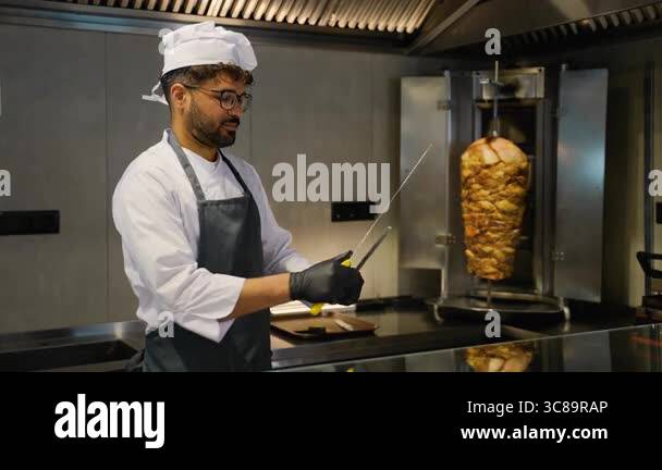 Chef in white uniform and black gloves sharpening a knife with a honing ...