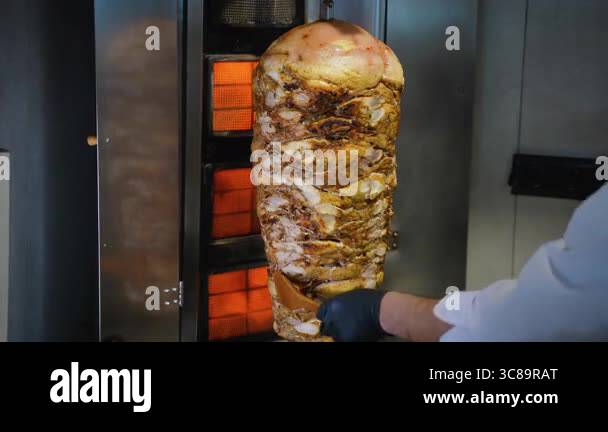 Close-up of juicy shawarma meat stack roasting on vertical rotisserie ...