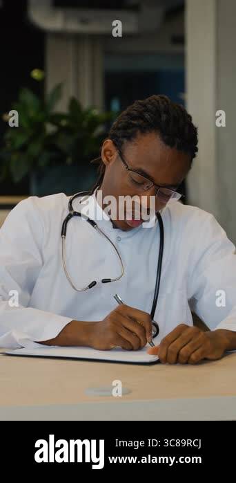 Tired doctor writing notes at end of workday. Exhausted male doctor in ...