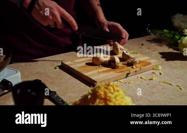 A chef chops mushrooms on a wooden board, preparing fresh ingredients ...