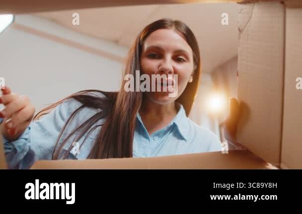 Happy woman unpacking delivery parcel at home. Smiling satisfied young ...