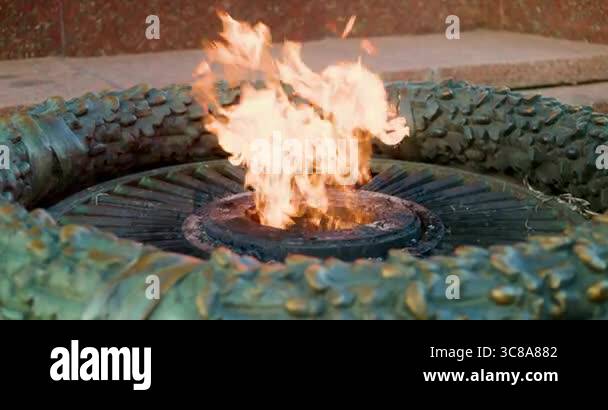 Close-up of an eternal flame at a war memorial, symbolizing remembrance ...