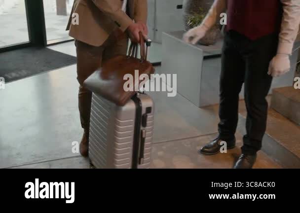 Businessman entering hotel lobby, leaving luggage with bellboy, then ...