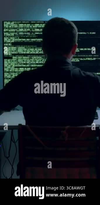 Anonymous male hacker from behind with headphones in front of several ...