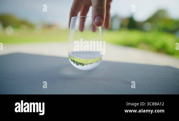 Shot of a mans hand grabbing a glass of water and swirling it gently ...