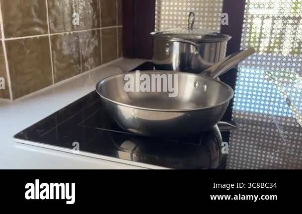 Stainless steel cookware and kitchen utensils on shelf, symbolizing ...