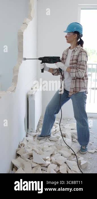 Female construction worker demolishing a wall with a hammer drill ...
