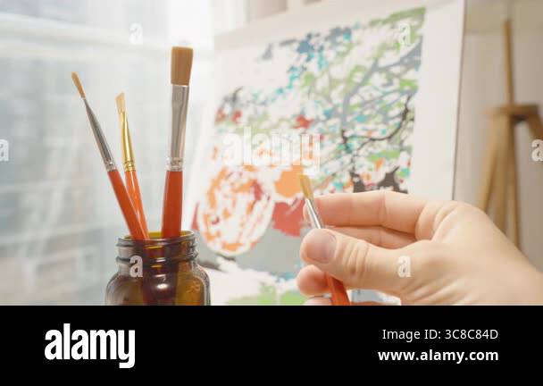 Hand Selecting a Fan Tip Paintbrush from a Jar with Other Brushes as ...