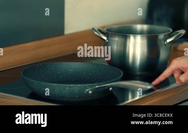 Turning on induction cooktop to heat frying pan. Activating touch ...