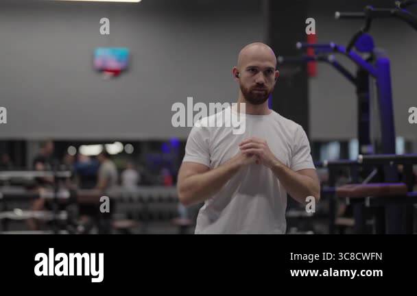 Bald man warming up before starting his fitness workout at the gym ...