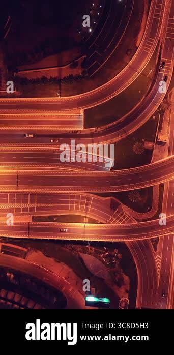 Top view of glowing night traffic weaving through highway interchanges ...