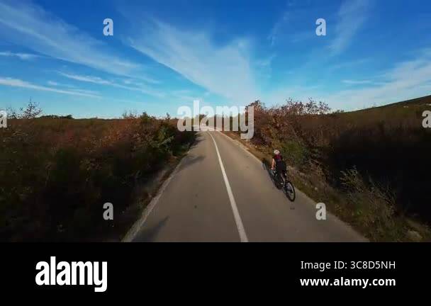 Cyclist on winding mountain road at sunset surrounded by vibrant autumn ...