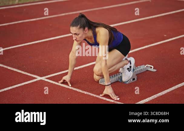 Female Runner on Athletics sprint race starting blocks on a dark ...