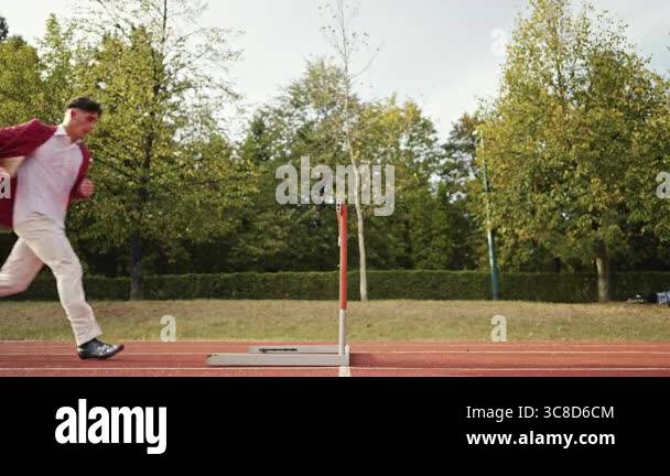 Businessman jumping a hurdle while running on the athletics racing ...