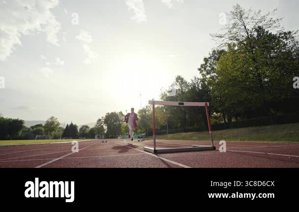 Businessman jumping a hurdle while running on the athletics racing ...