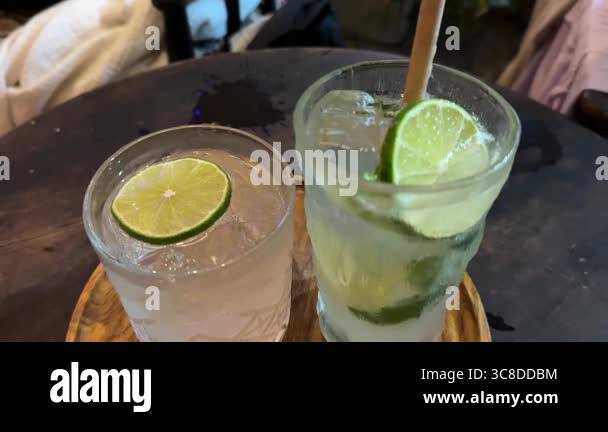 Two alcoholic drinks are on the table: a cocktail with lime, Mojito and ...