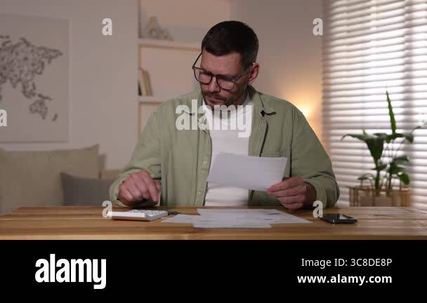Paying bills. Man with calculator and invoices at wooden table indoors ...