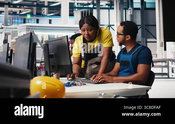 Engineers monitor solar system software at desk in modern factory, team ...