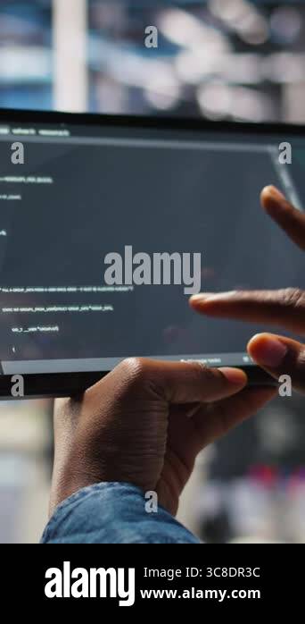 Vertical video Close up of server room programmer checking coding on tablet enhancing ...