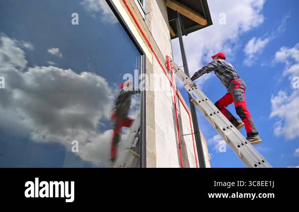 Man Climbs Ladder to Work on Building Exterior on a Sunny Day With ...
