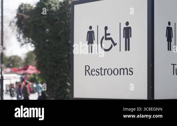 Sign indicates restroom facilities for all visitors in a busy area ...