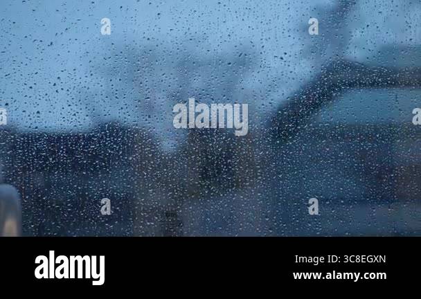Capturing the soothing ambiance of rain hitting glass in a busy area ...