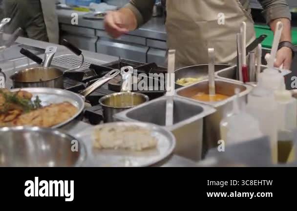 Professional chef working in a commercial kitchen preparing a meal with ...
