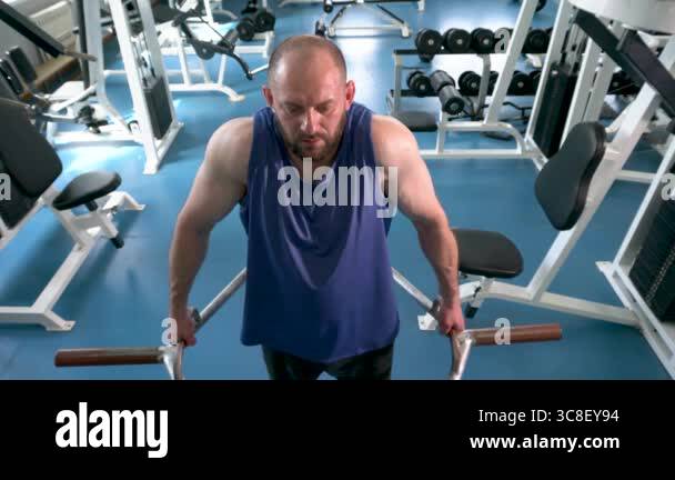 A man works out in a gym using a weight machine. The gym is clean and ...