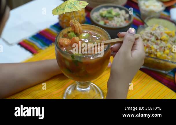 Mexican woman alone at home eating shrimp cocktail. Close up to the ...