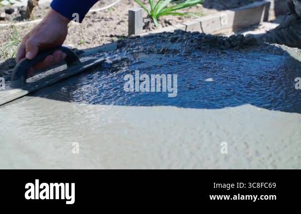 A mans hand is leveling fresh concrete with a trowel. High quality ...
