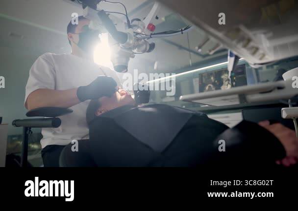Male dentist working with dental microscope in modern stomatology ...