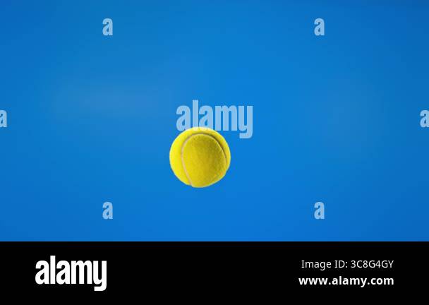 Tennis ball flying and spinning in ultra slow motion against a blue ...