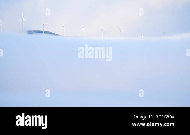 Wind turbines farm on hill in foggy landscape. Windmill covered with ...
