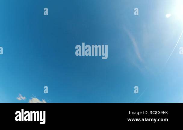 timelapse of blue sky with sparse clouds and distant plane under bright ...