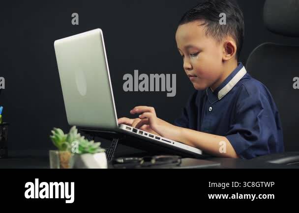 a boy is learning to type using a laptop to do his schoolwork ...