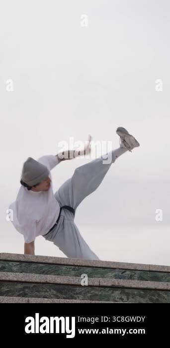 Urban breakdancer performing challenging acrobatic moves on building ...