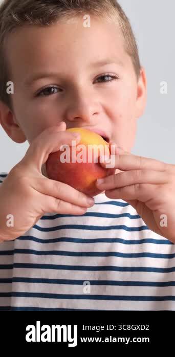 A young boy is happily munching on a delicious, juicy apple, showcasing ...