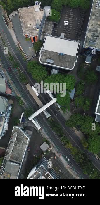 Overhead view of city street, buildings, pedestrian bridge, and lush ...
