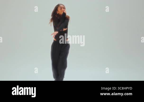 An energetic young girl performs an expressive solo dance in a bright white studio, showcasing ...