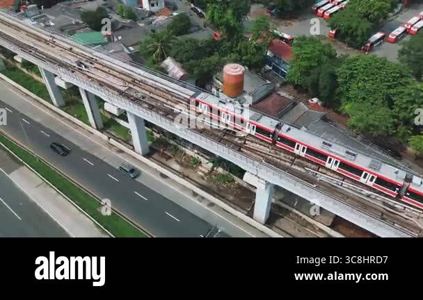Aerial view of a train on an elevated track beside a highway, passing ...