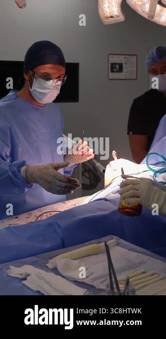 Experienced surgeons in blue coats operate on a military patient in a ...