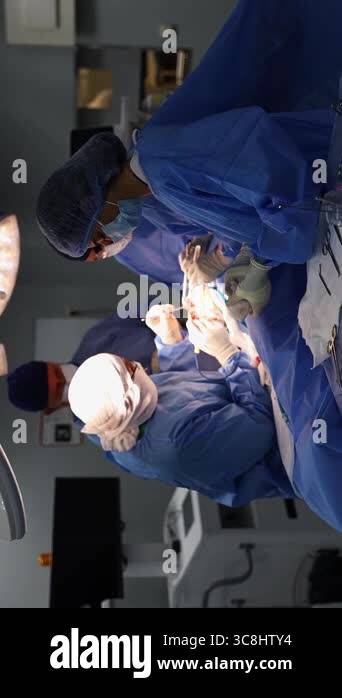 Experienced surgeons in blue coats operate on a military patient in a ...
