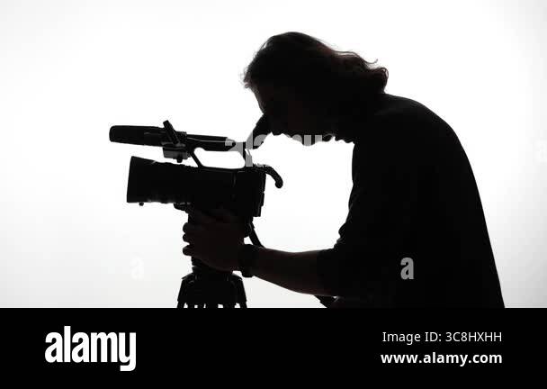 Silhouette of a person filming with a professional video camera ...