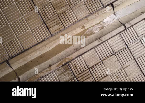 Ceramic floor tiles with grooved texture and a rain water in the ditch ...