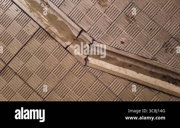 Ceramic floor tiles with grooved texture and a rain water in the ditch ...